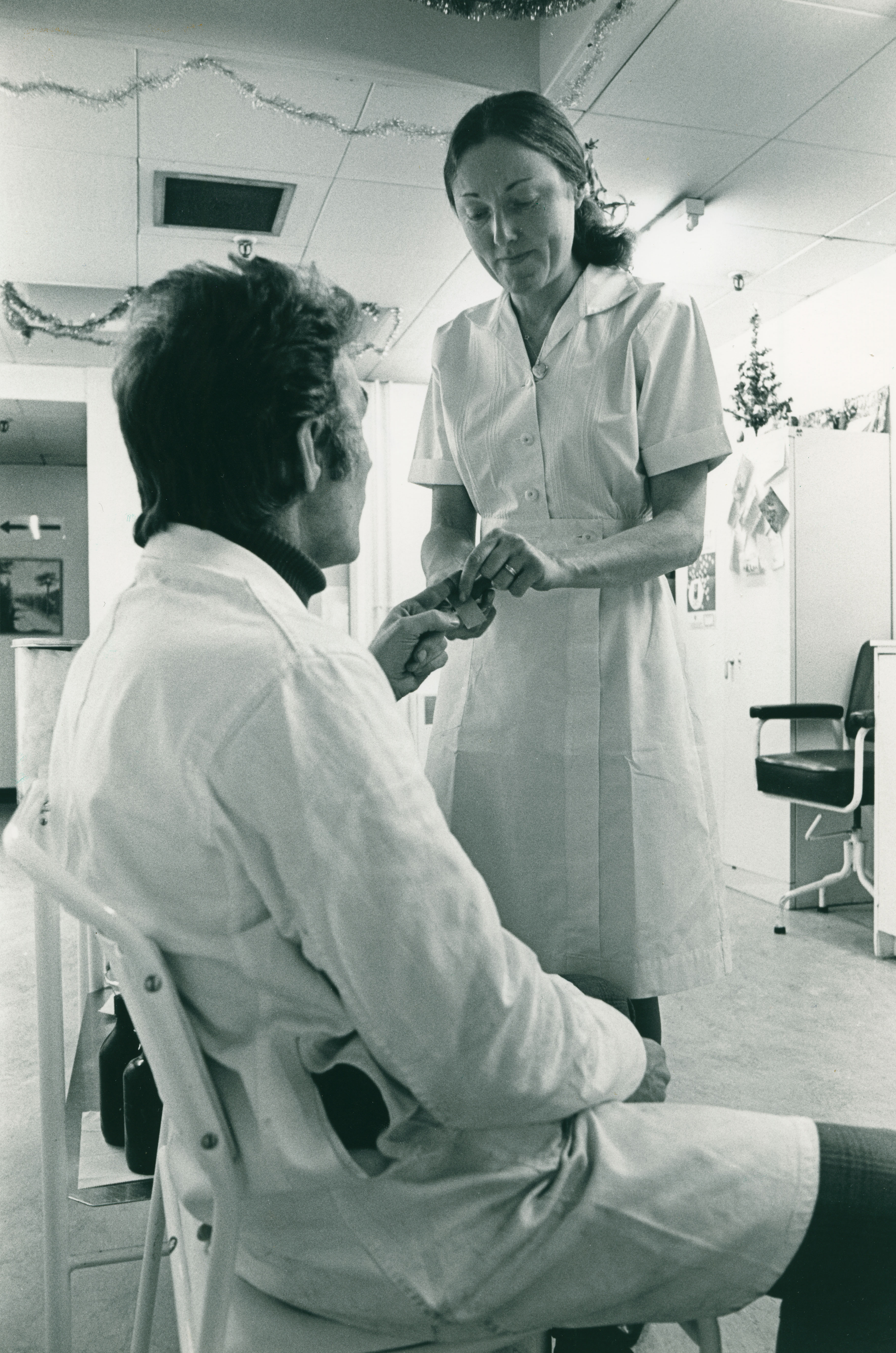 Image of Aileen Chan, night sister, applying a plaster to an employee ...